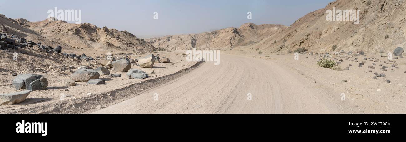 landscape with bending gravel road and baslat boulders among rocky ...
