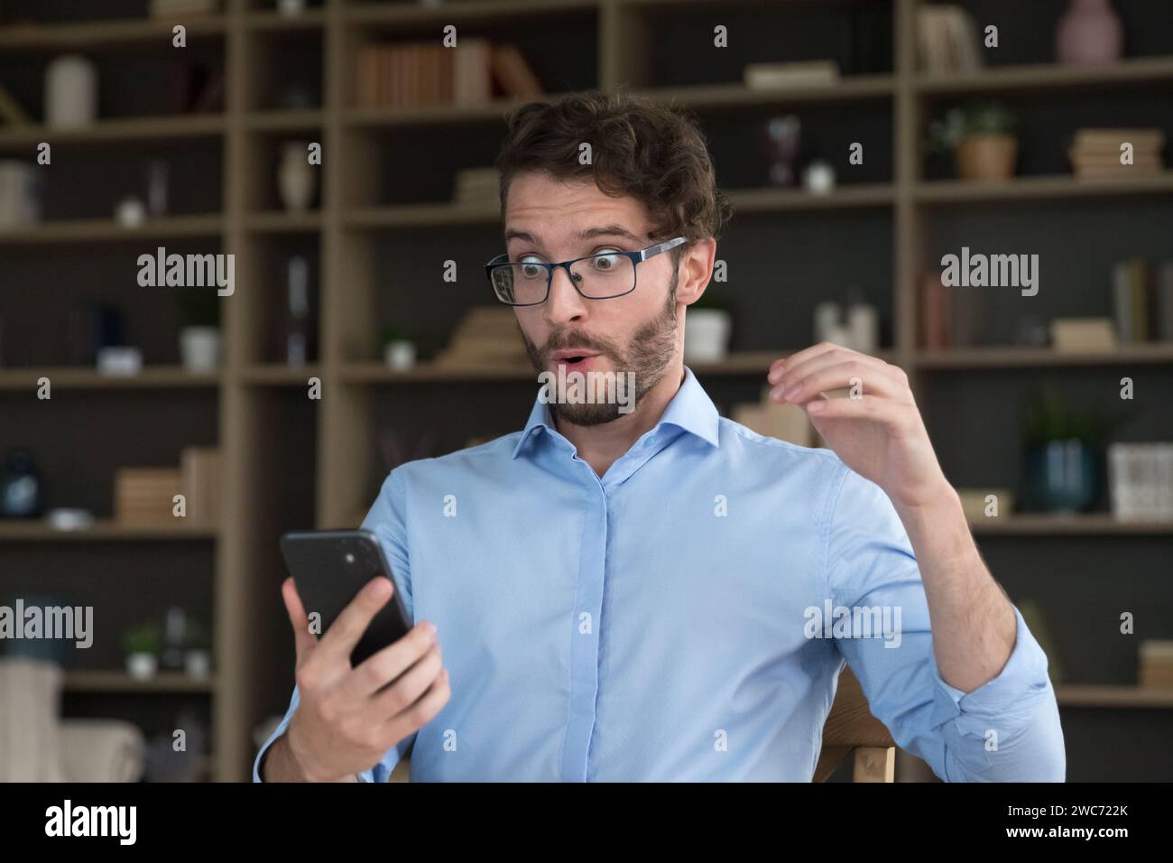 Stunned amazed guy goggle his eyes staring at smartphone screen Stock ...