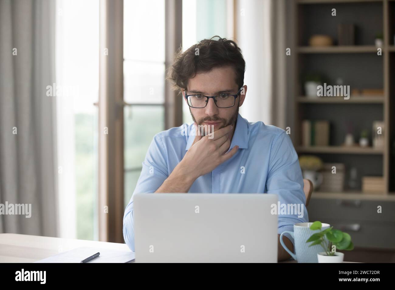 Serious thoughtful millennial man staring at laptop, read received ...