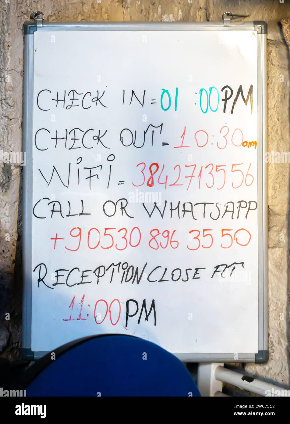 Reception of a hostel board with check-in and check-out times, and ...