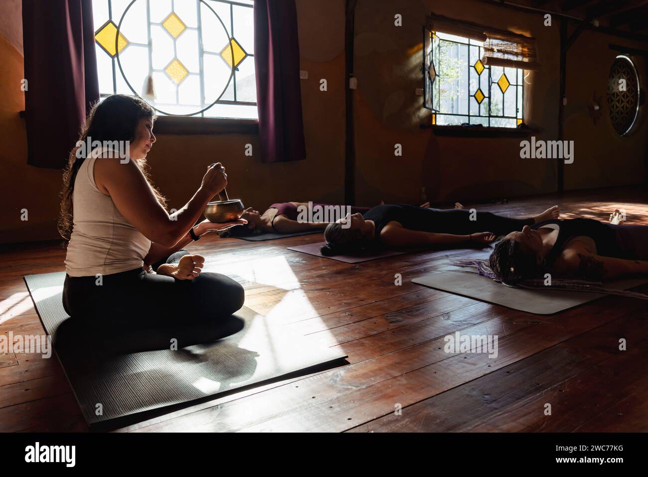 Woman in lotus position leading a meditation session. Relaxing moment after group yoga class ...