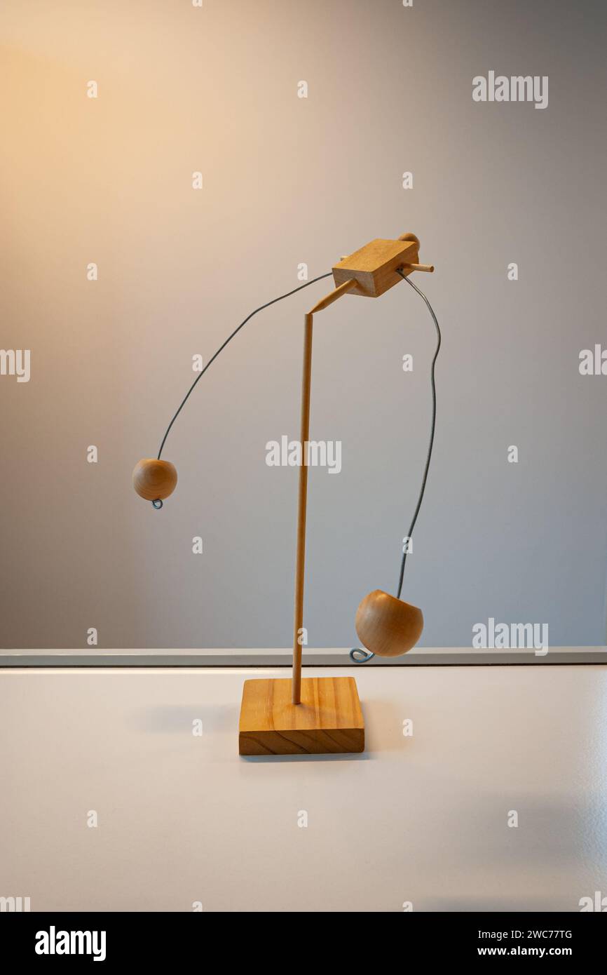 Wooden figure on a stick where the center of gravity is below the pivot ...