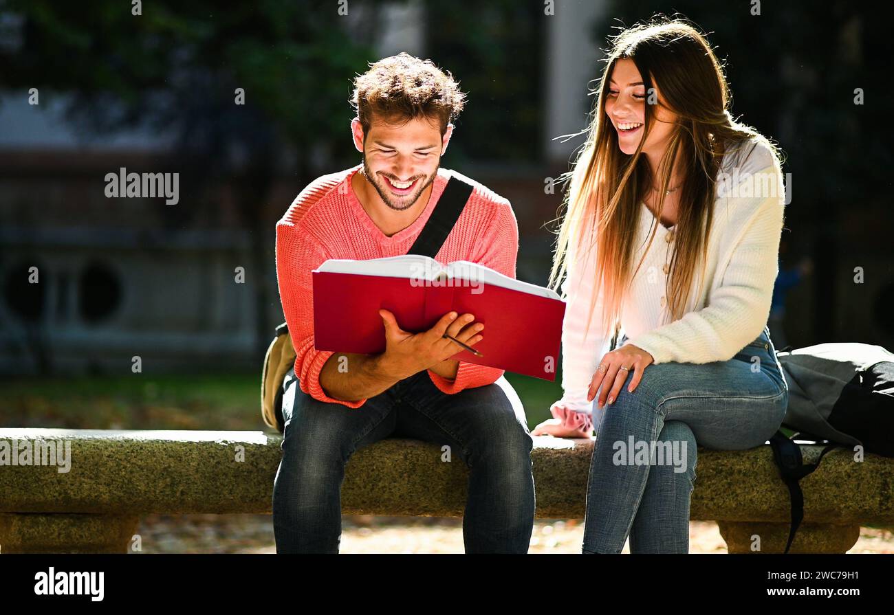 Two students studying together sitting on a bench outdoor Stock Photo ...