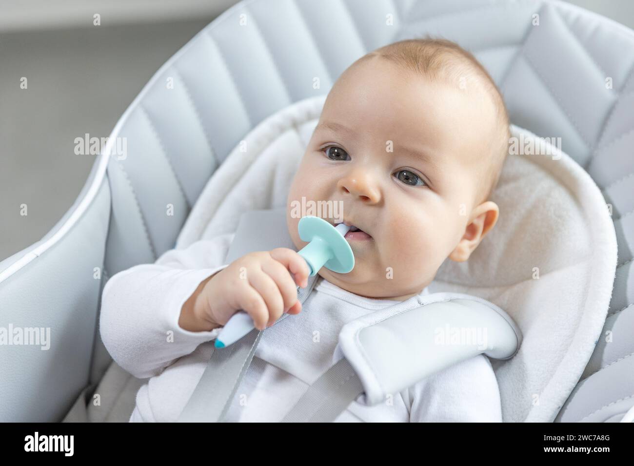 Teeth growth concept, newborn baby with a teether in his mouth for ease ...