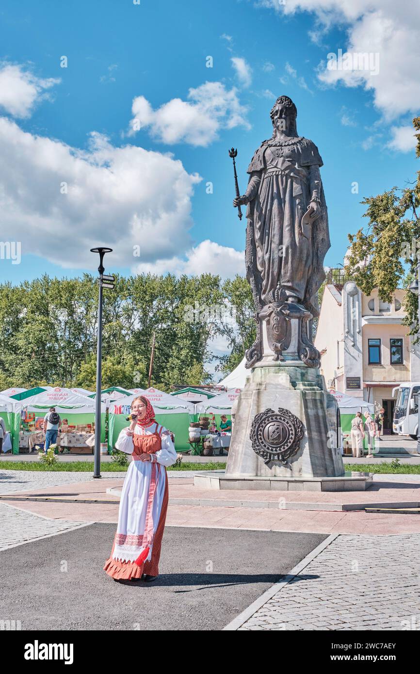 Girl in Russian national costume singing into microphone on square ...