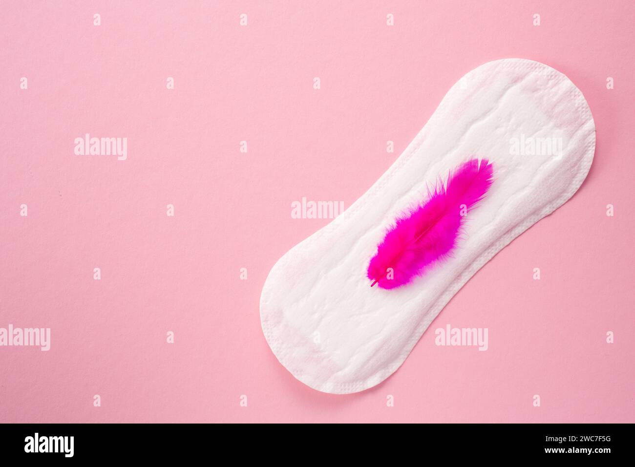 Feminine hygiene pad with red feather on menstrual pad on pink ...
