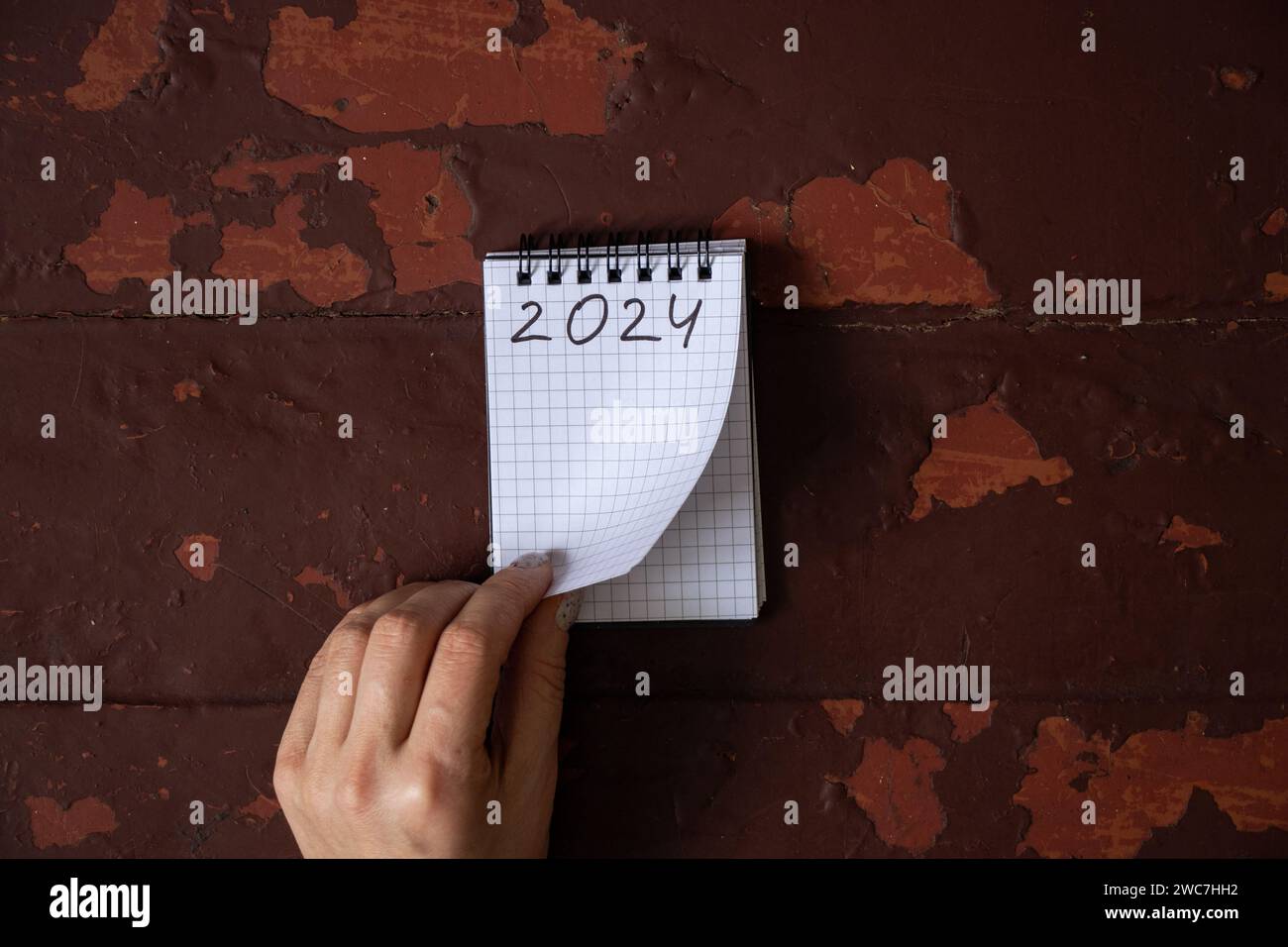 Notepad with text 2024 and female hand turning page on wooden weathered ...