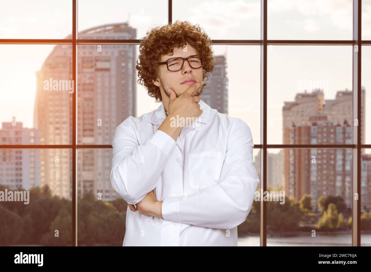 Portrait of a smart young man with glasses thinking about something ...