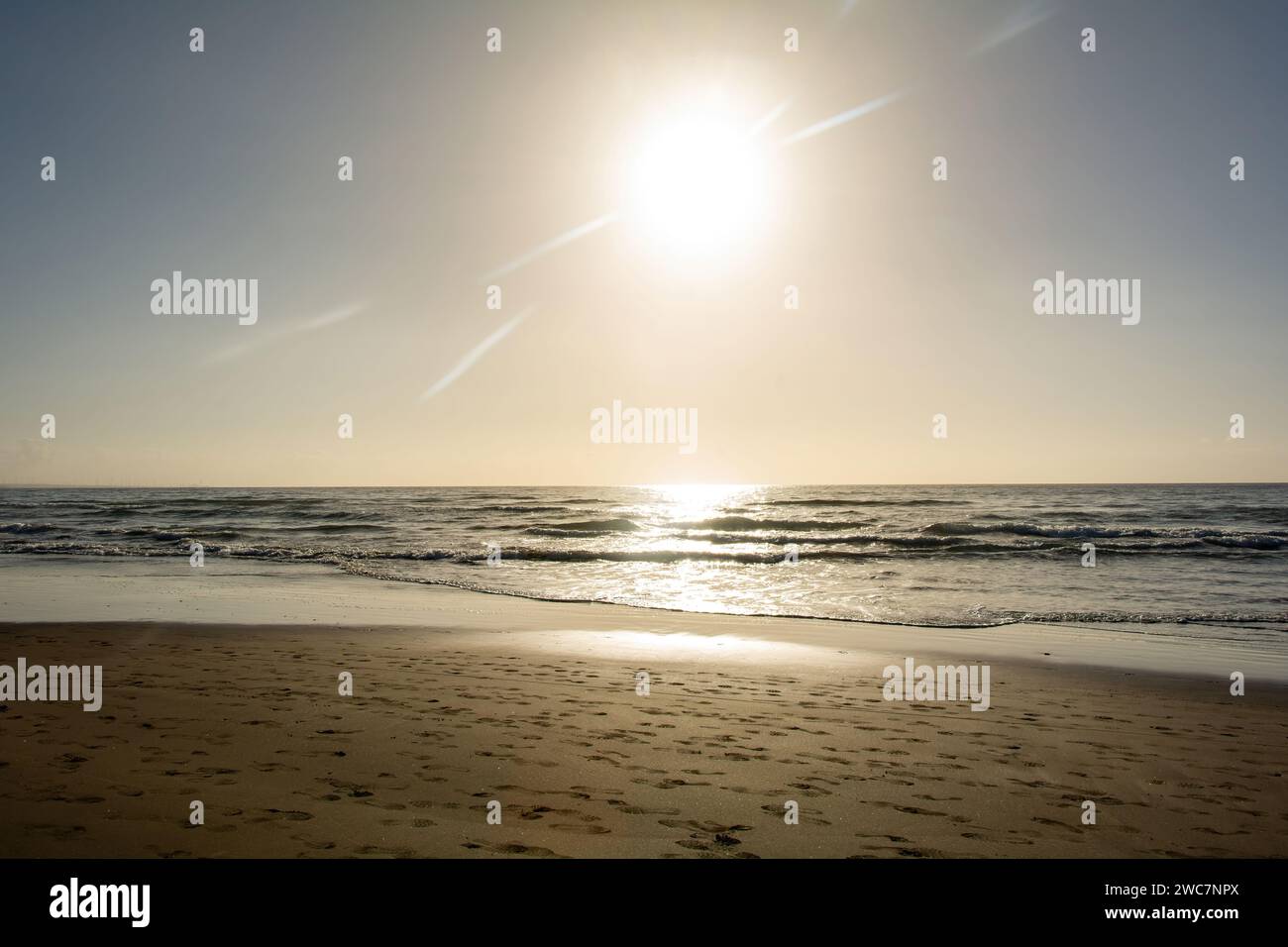 Sandy beach by the sea with waves and sun Stock Photo - Alamy
