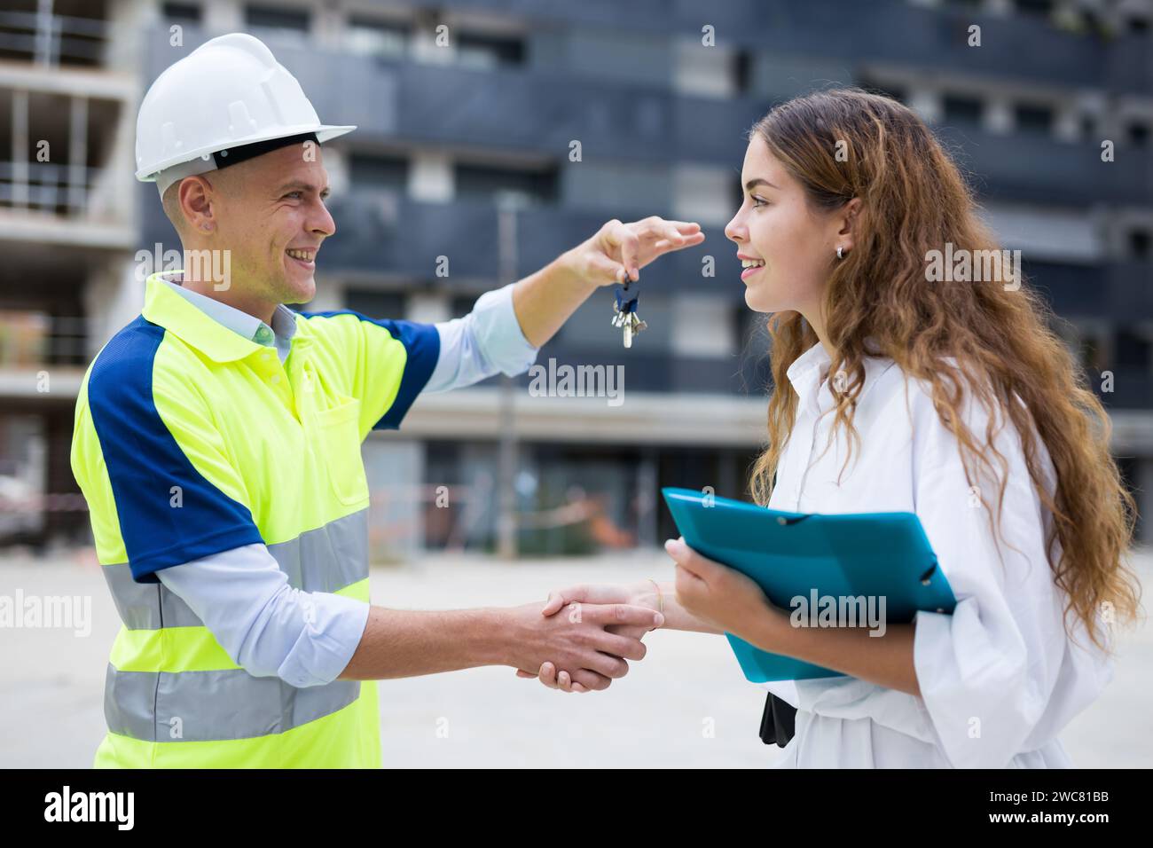 Builder giving keys to woman in construction site Stock Photo - Alamy
