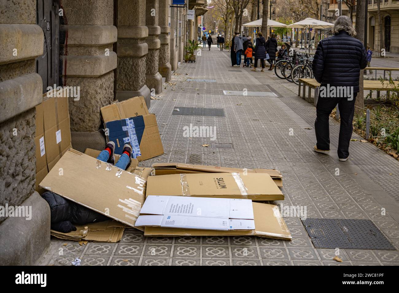 A man is seen practically covered in cardboard in an improvised space ...