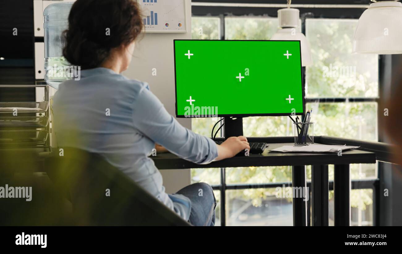 Specialist watches greenscreen desktop sitting at office desk, checking blank chromakey display ...