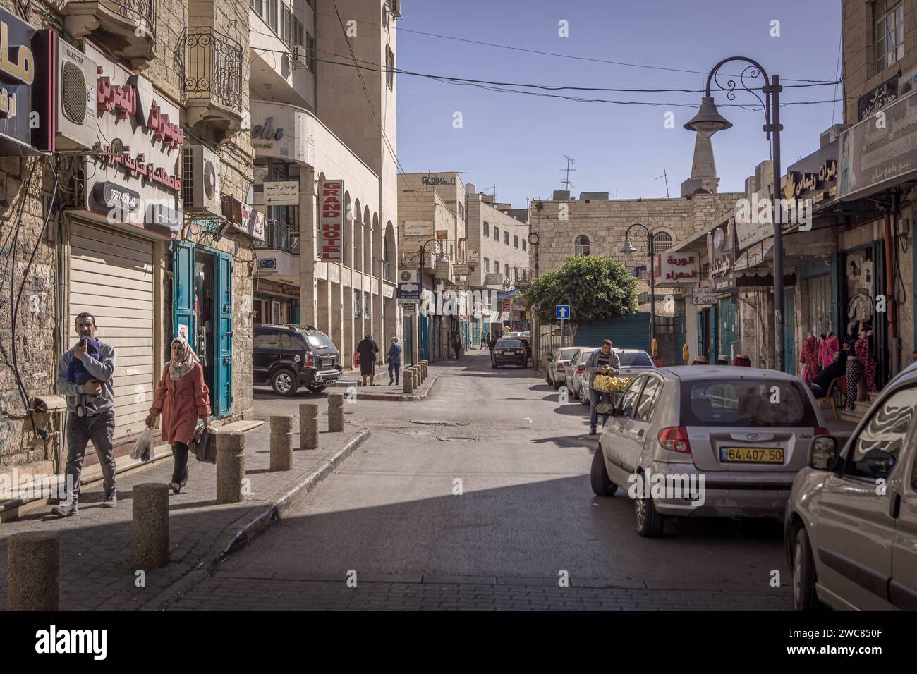 The city streets of Bethlehem, West Bank, Palestine, with cars, buildings, vendors' shops ...