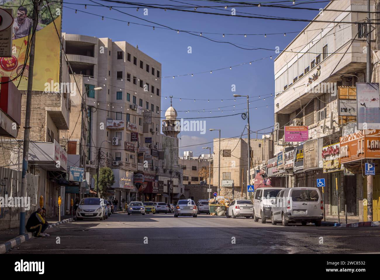 The city streets of Bethlehem, West Bank, Palestine, with cars, buildings, vendors' shops ...