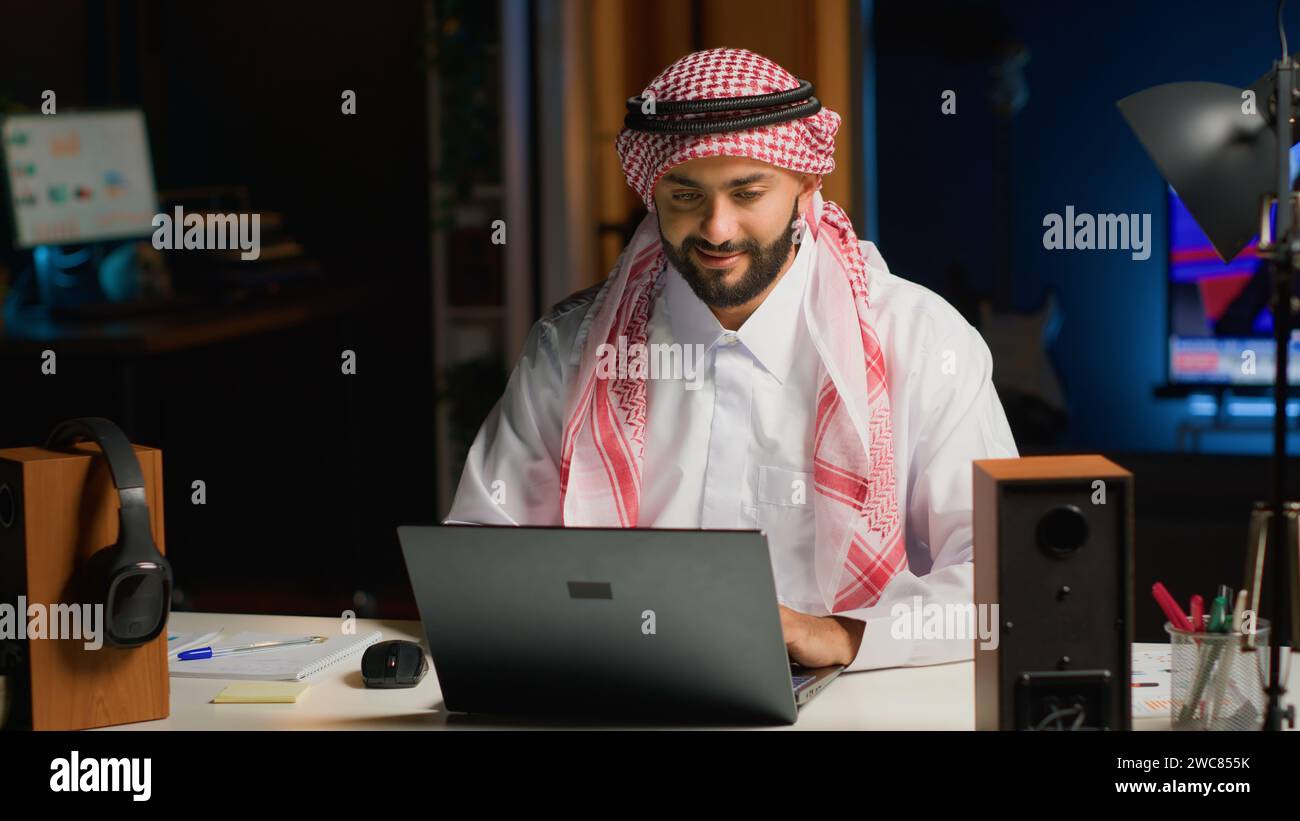 Arab businessman typing on laptop, surfing the net while at living room ...