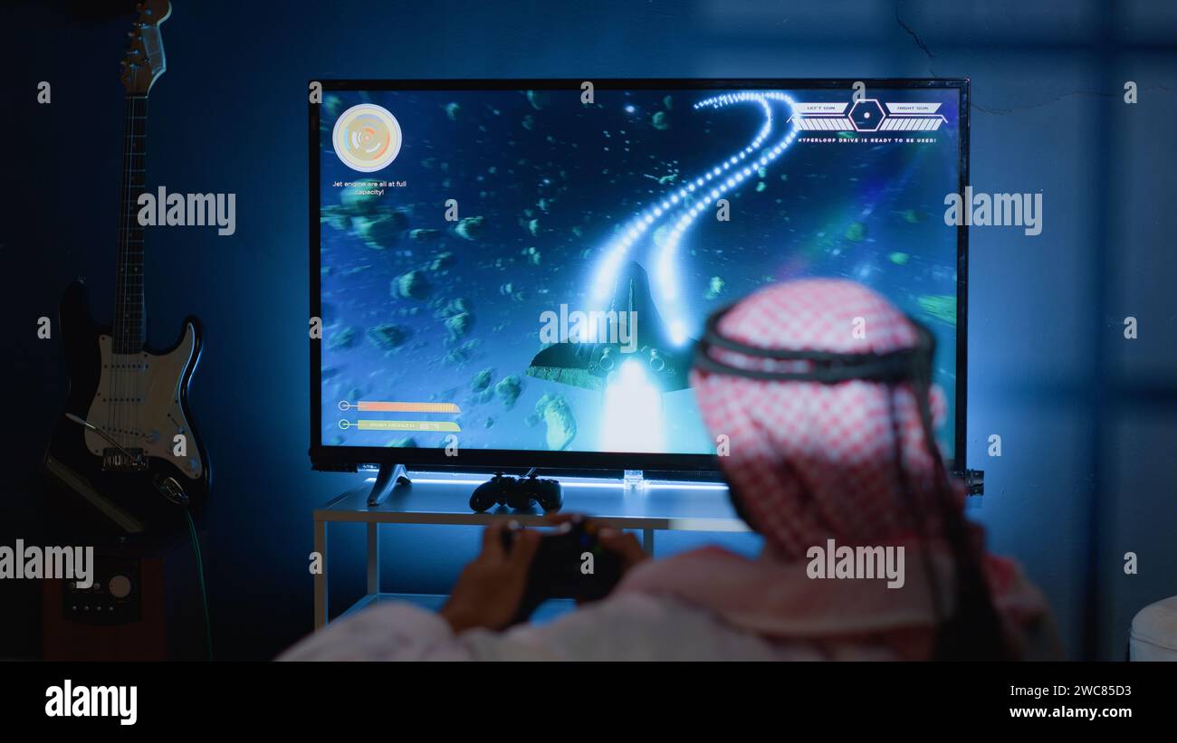 Middle Eastern gamer plays classic arcade action videogame, flying ...