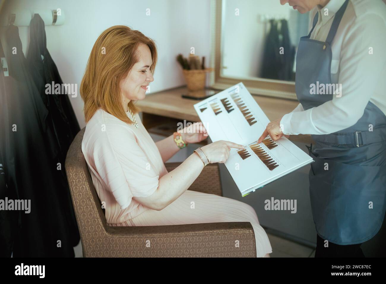 pensive 40 years old woman hairdresser in modern hair studio with hair ...