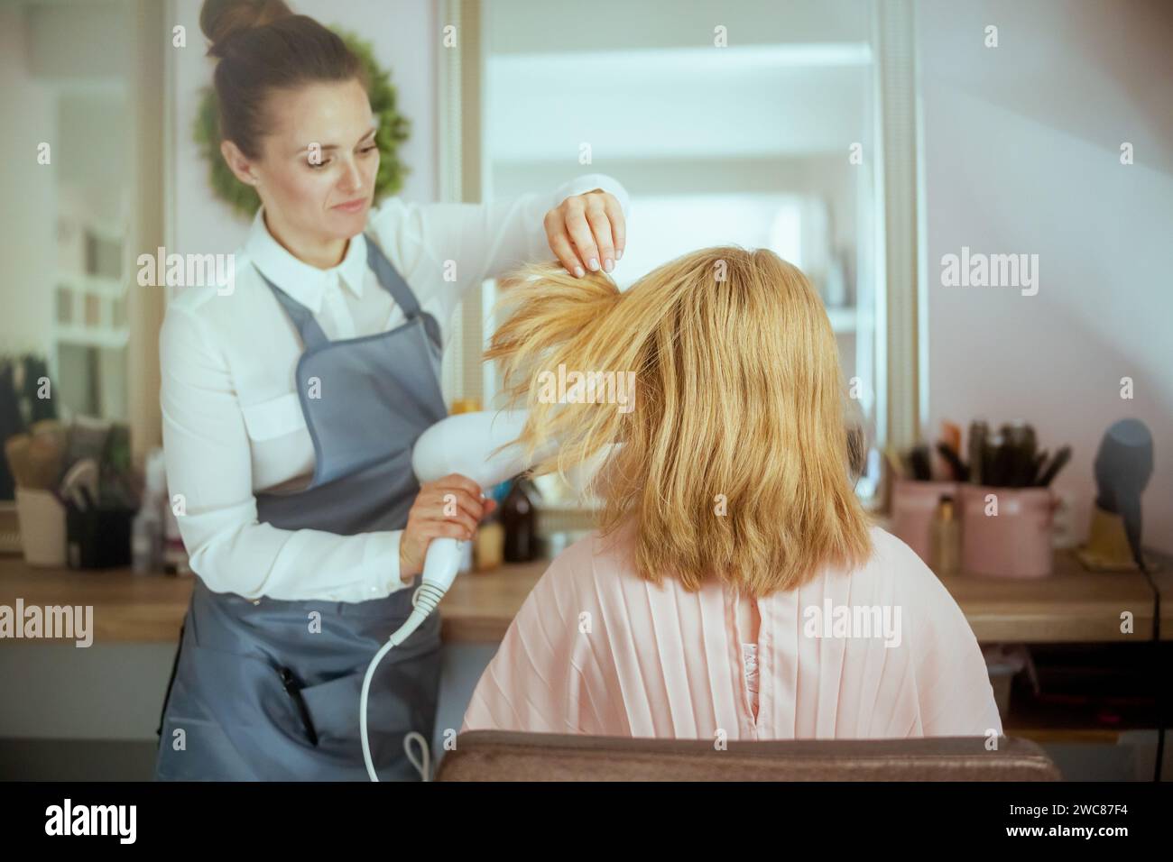 pensive woman hair salon worker in modern beauty studio with client ...