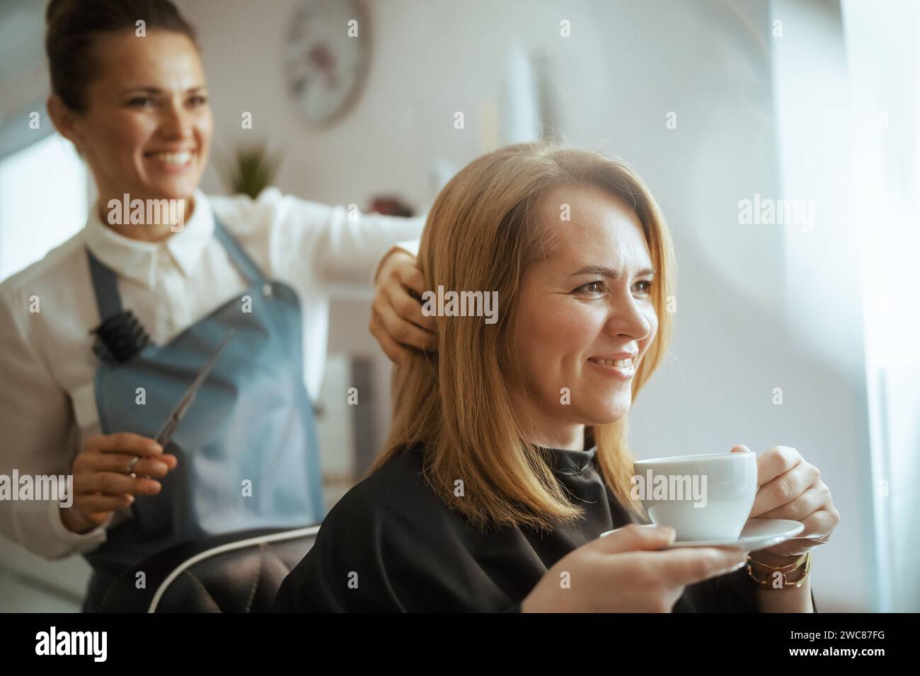 40 years old hair salon employee in modern beauty salon cutting hair ...