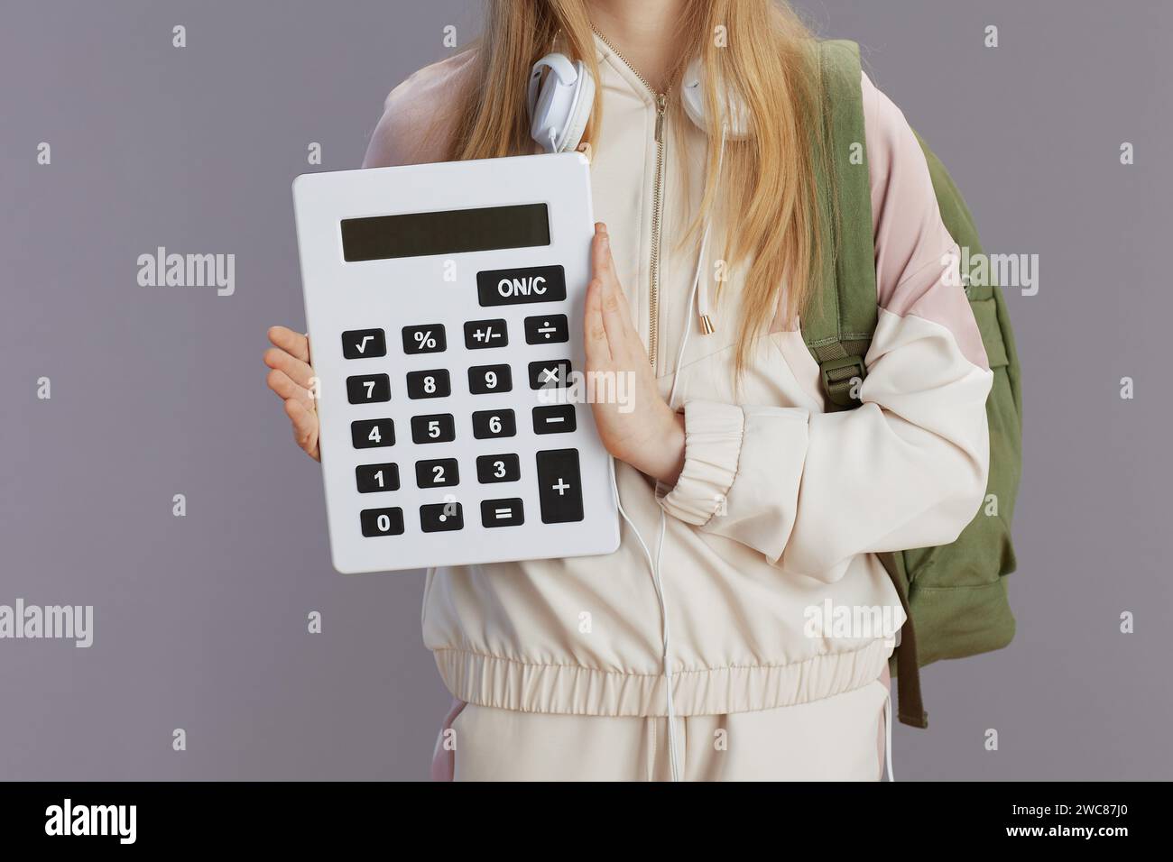 Closeup on school girl in beige tracksuit with backpack, calculator and ...