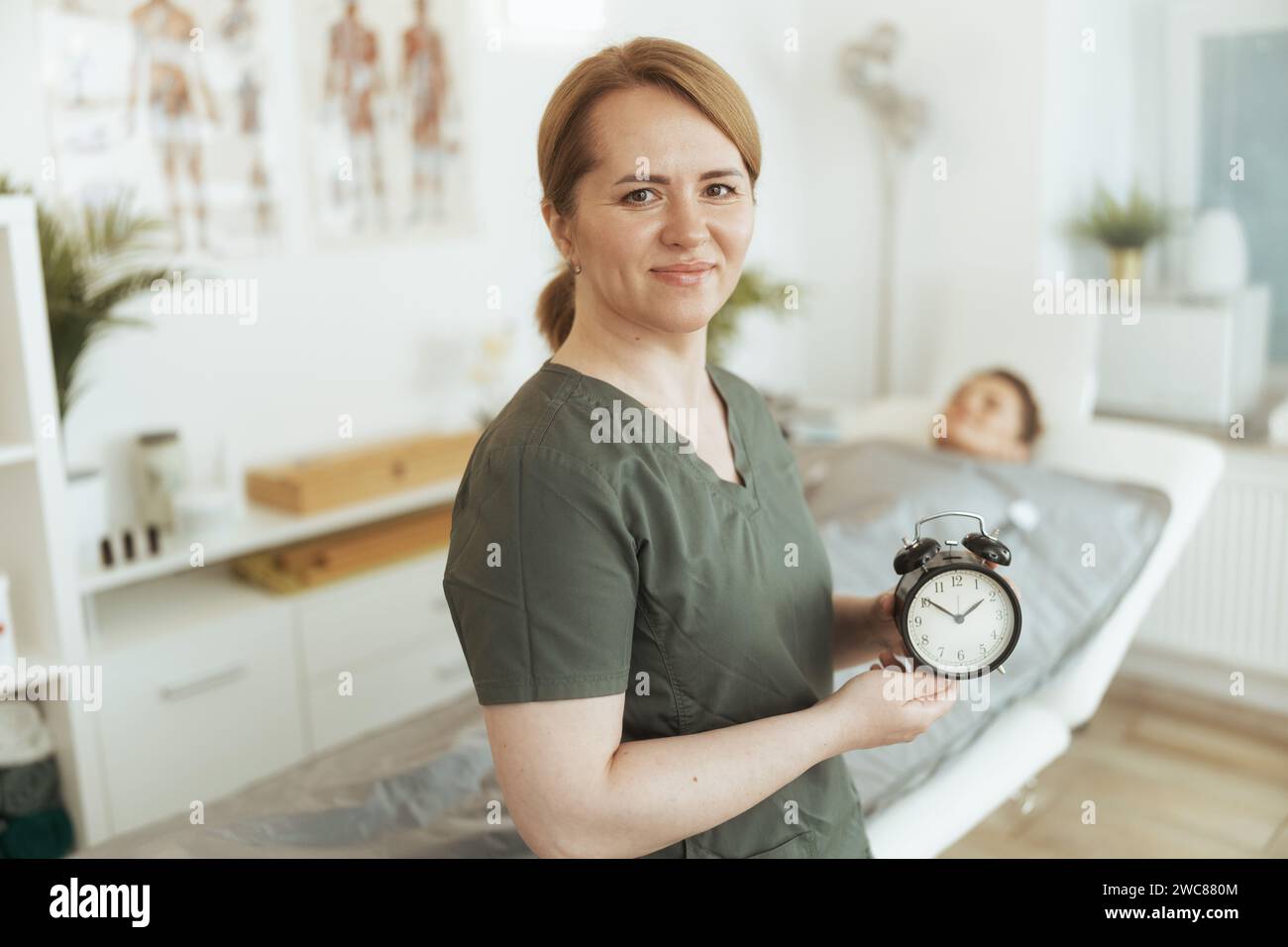 Healthcare time. happy female medical massage therapist in massage cabinet with client doing ...
