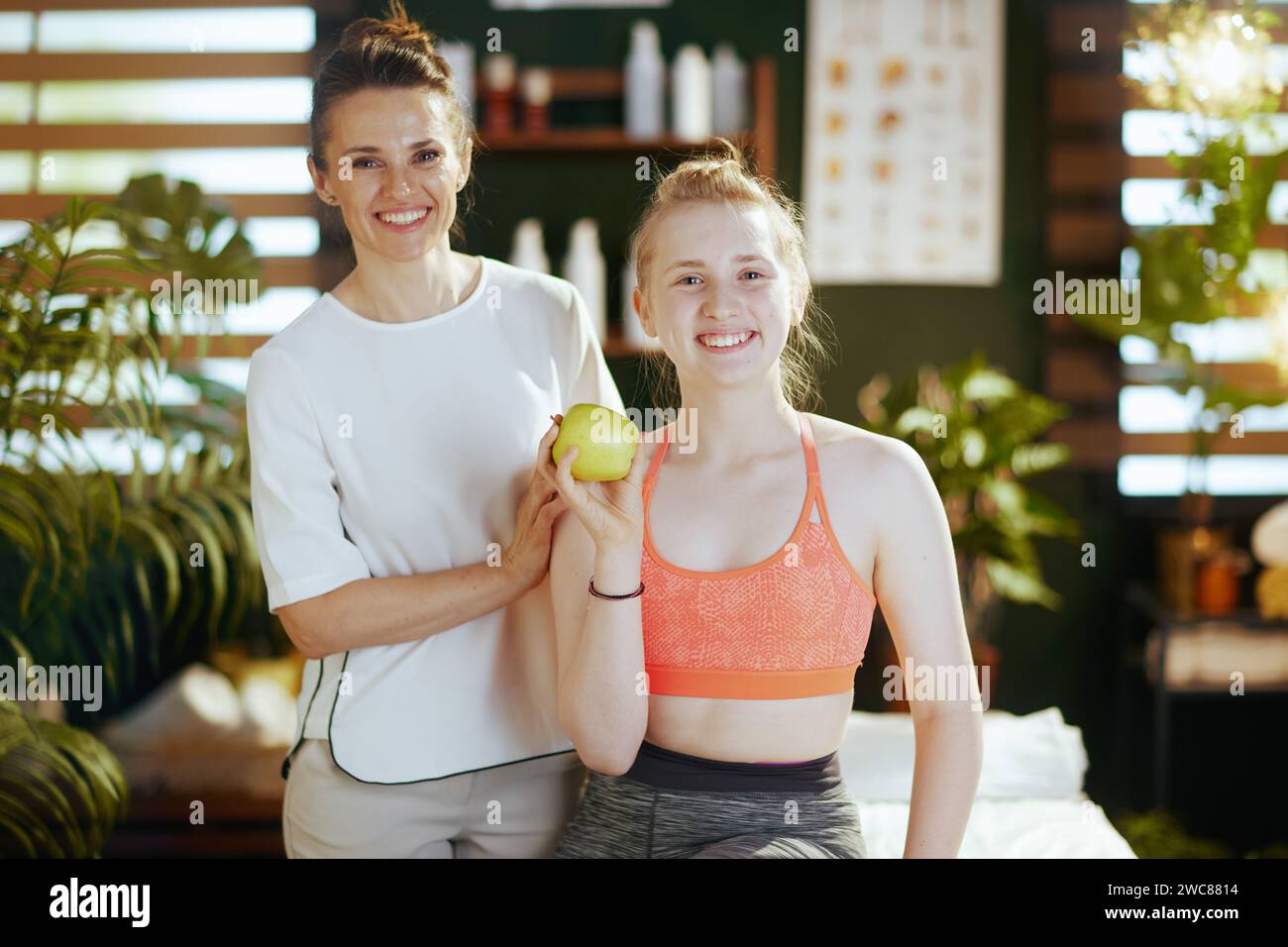 Healthcare time. happy female massage therapist in massage cabinet with teenage client and an ...