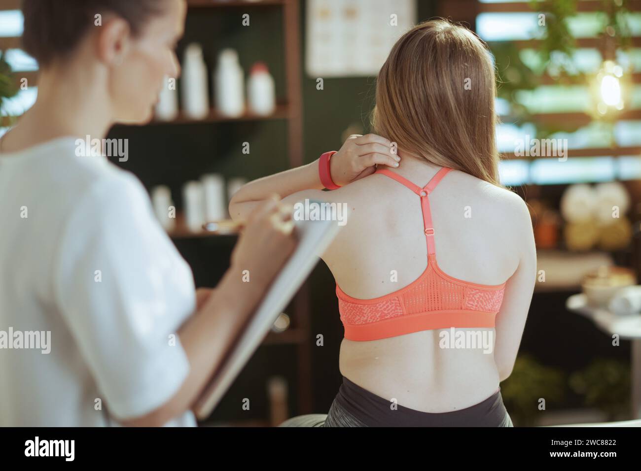 Healthcare time. female medical massage therapist in massage cabinet with clipboard and teenage ...