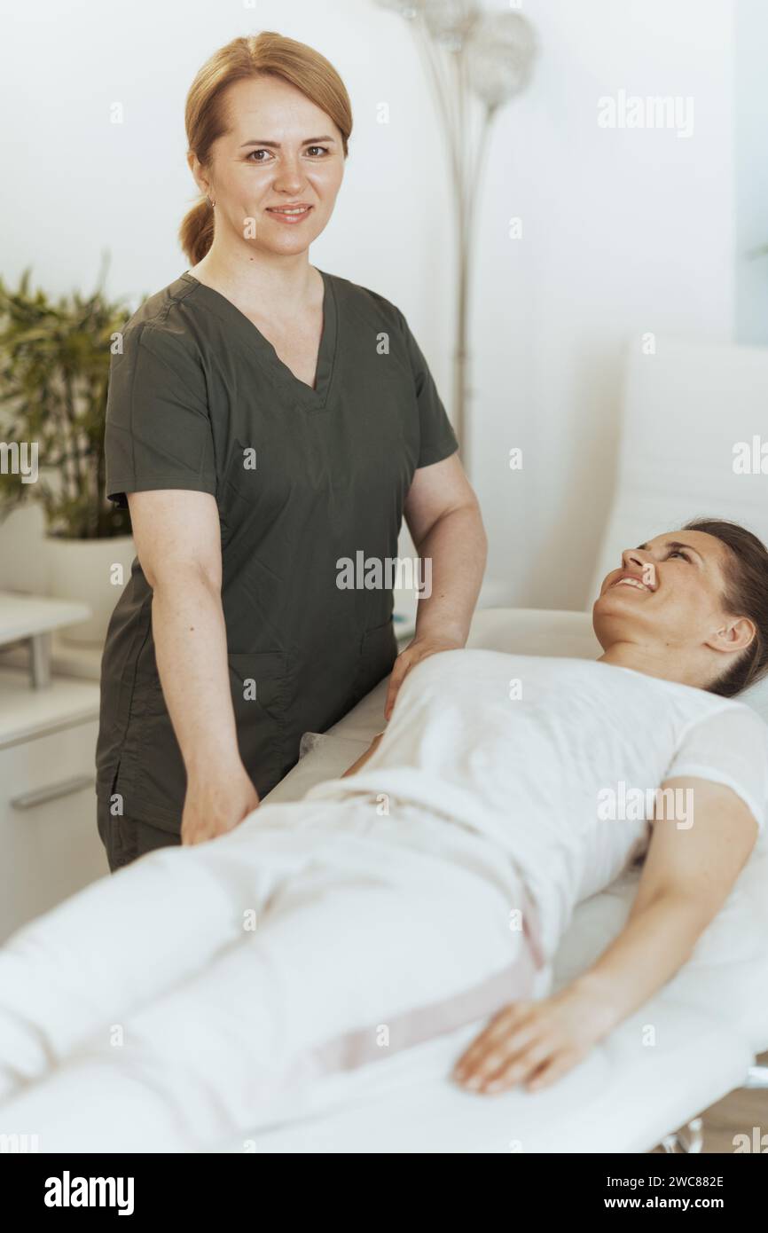 Healthcare time. smiling female massage therapist in massage cabinet with client doing checkup ...