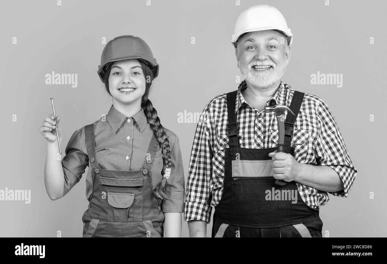 happy child and grandfather carpenter in hard hat on yellow background ...