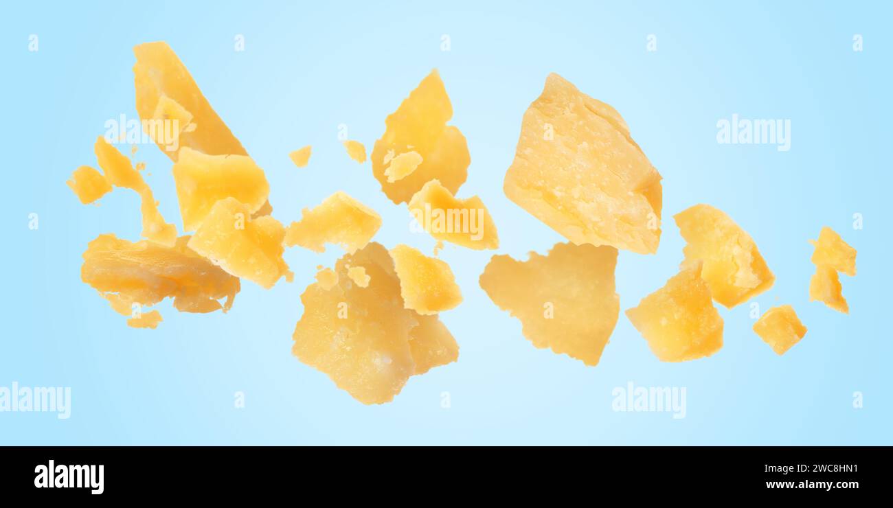 Tasty parmesan cheese falling on light blue background. Banner design ...