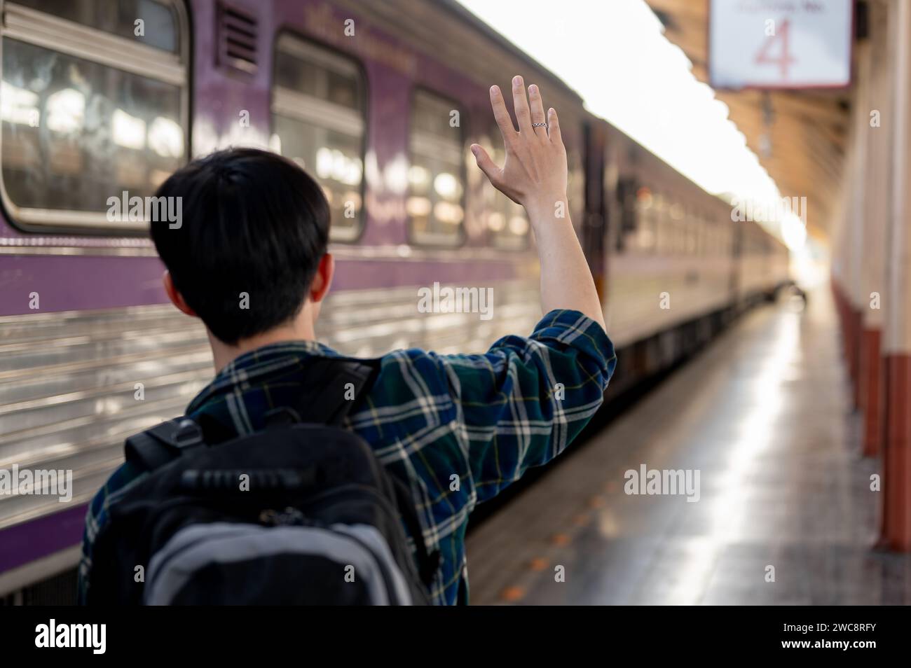 Back view image of a young Asian man waving his hand, say goodbye to ...