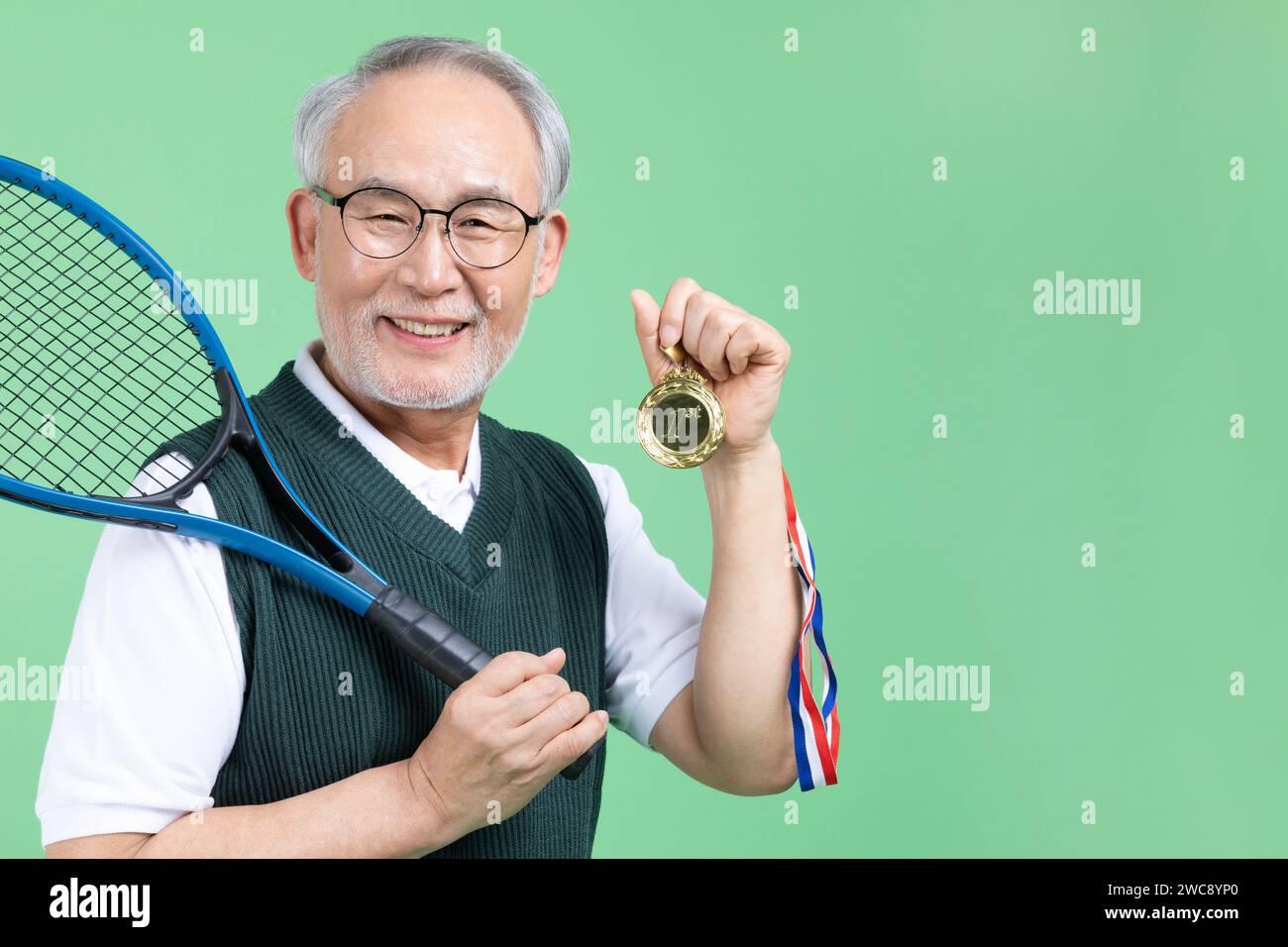 A senior male holding a tennis racket and a medal Stock Photo - Alamy
