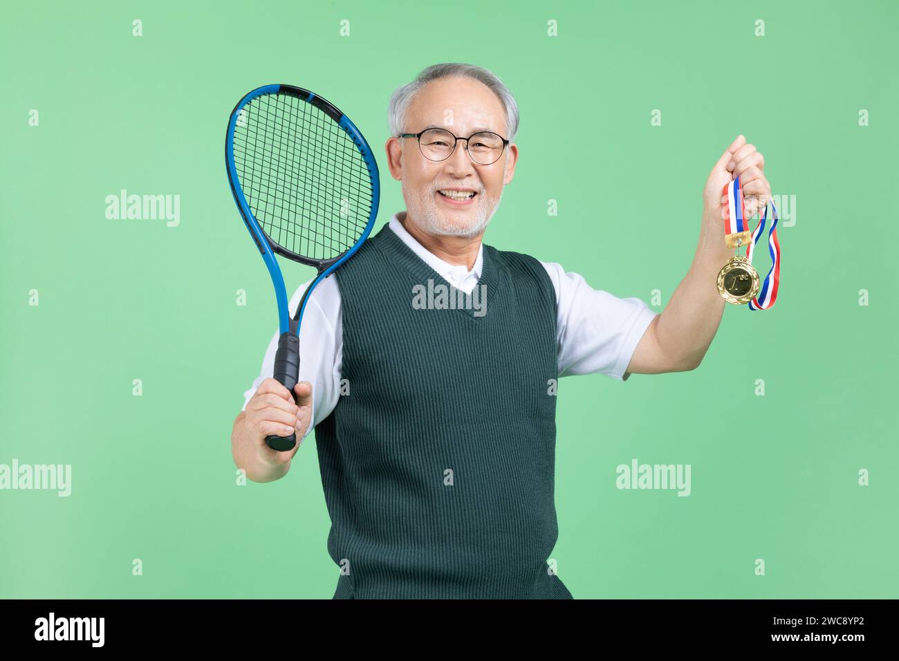 A senior male holding a tennis racket and a medal Stock Photo - Alamy