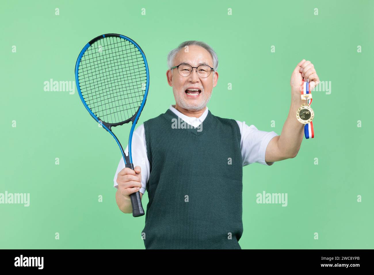 A senior male holding a tennis racket and a medal Stock Photo - Alamy