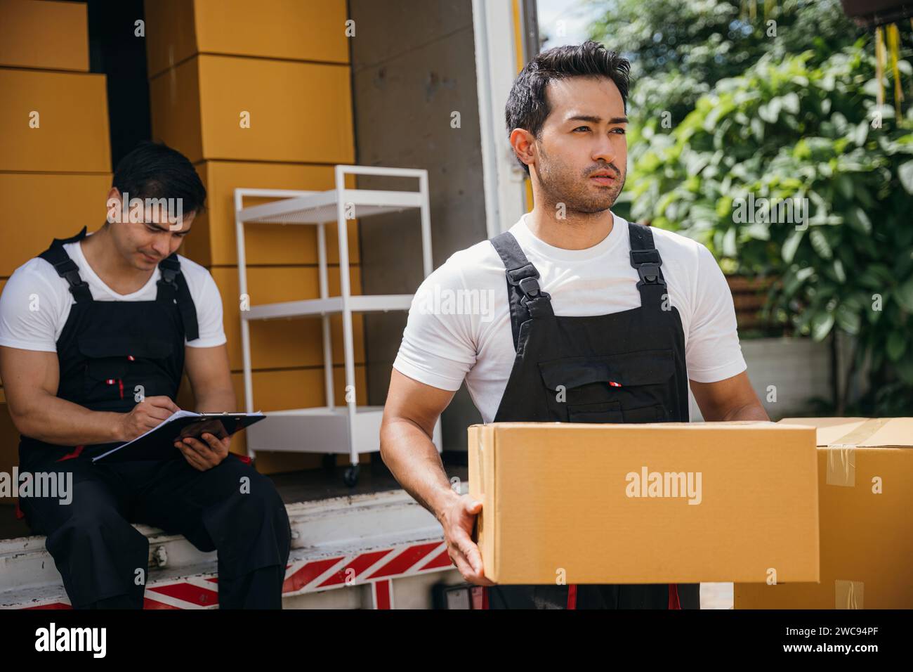 Uniformed workers unload boxes inspecting checklist with a clipboard at ...
