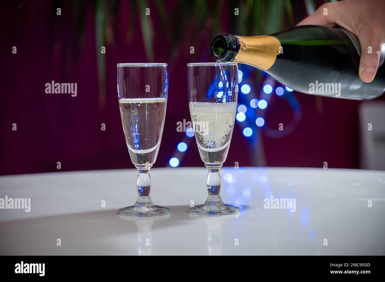 Pouring of brut champagne, cava or prosecco dry wine in glasses with ...