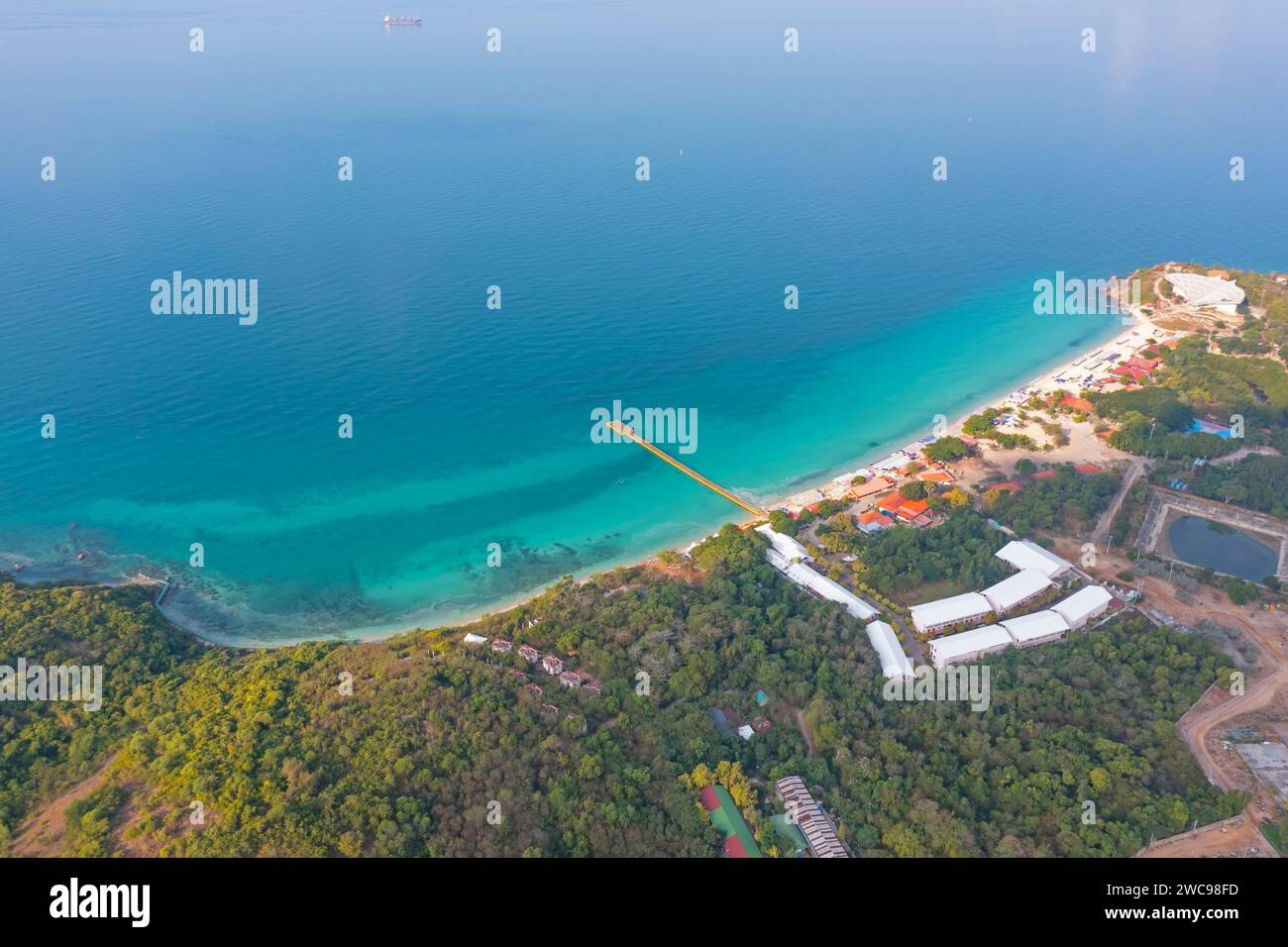 Tropical island with a sandy azure bay and pier and a beach village ...