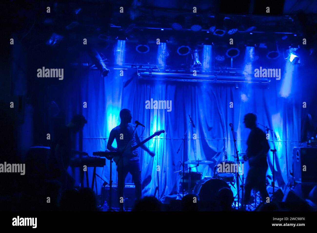 Silhouettes of musicians preparing on stage before a rock concert in ...
