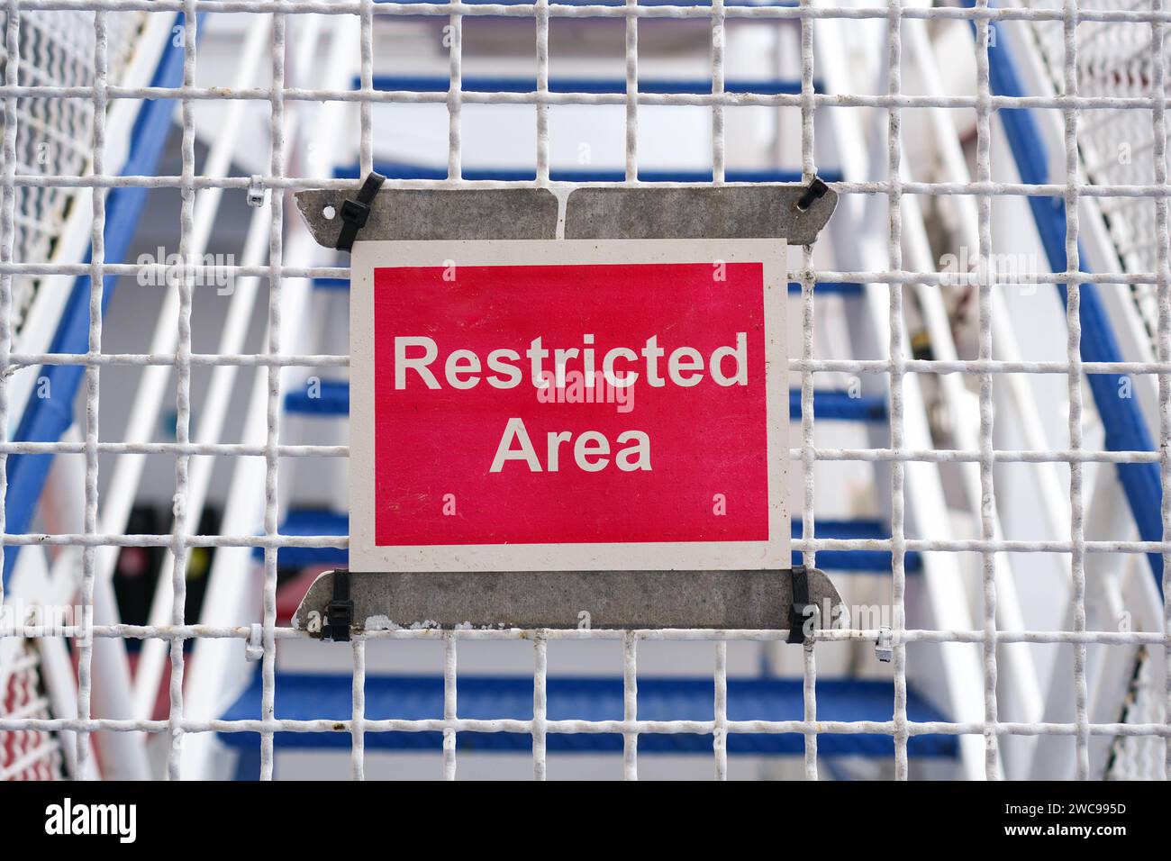 This is a close-up, horizontal shot of a vivid red Restricted Area sign ...