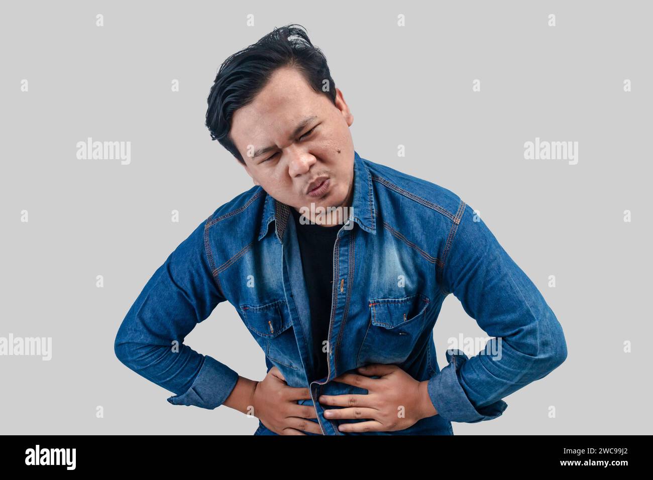 Young asian man having stomach ache or indigestion and pressing his ...