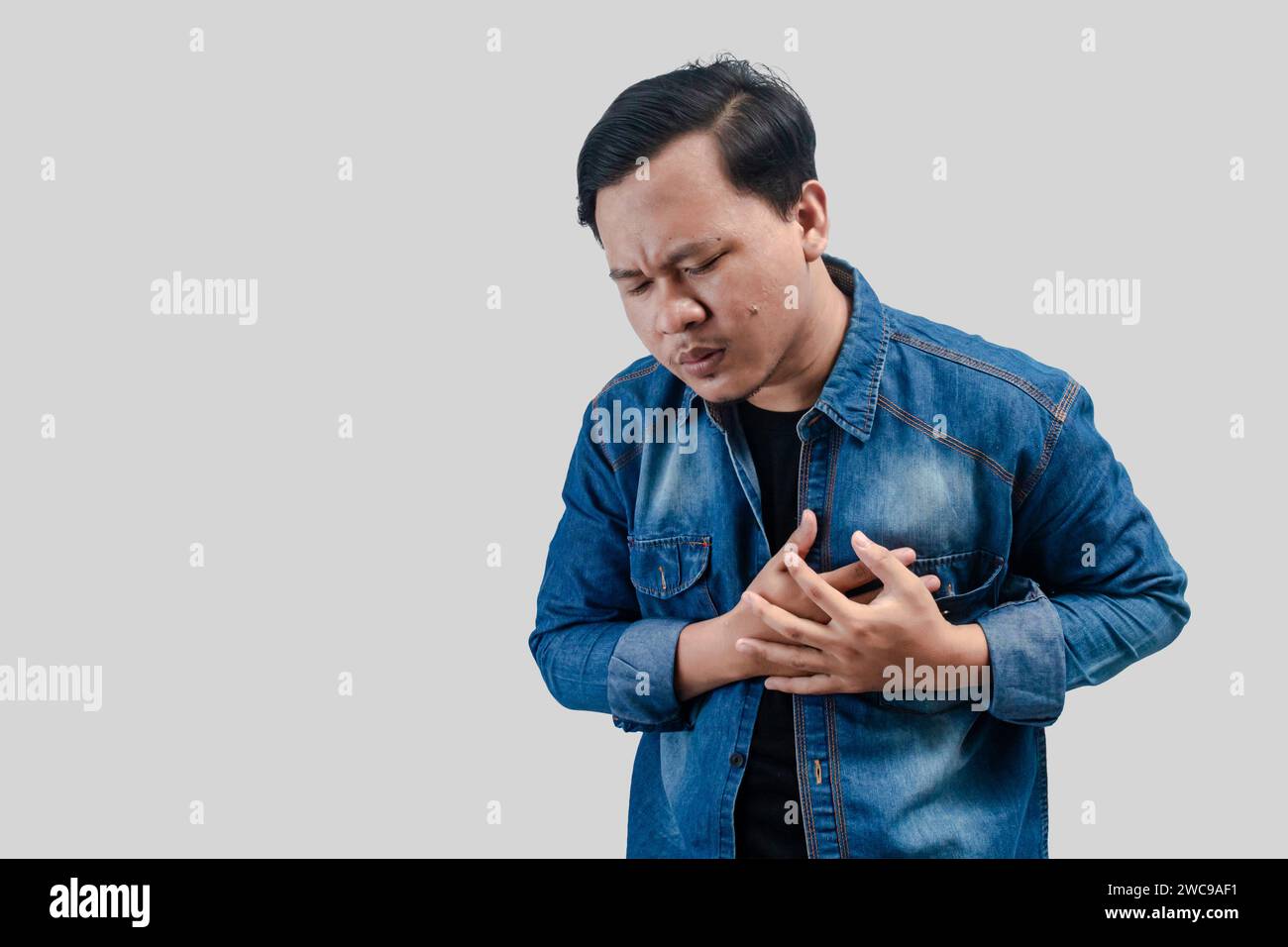 Young Asian man having chest pain or heart trouble and pressing his ...