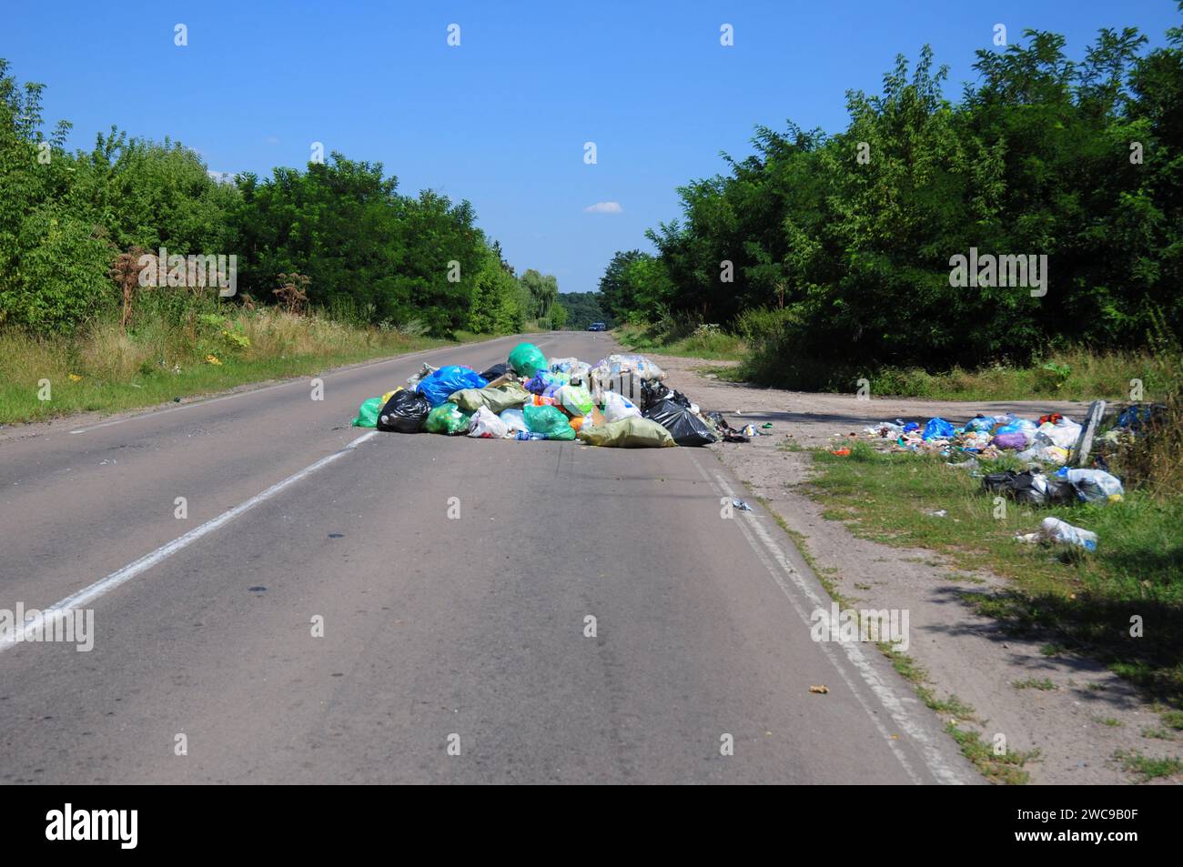 A garbage heap, junk heap, rubbish, trash pile blocking an asphalt road ...