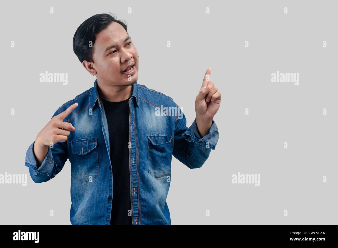 Young asian man pointing hand up to empty space on isolated background ...