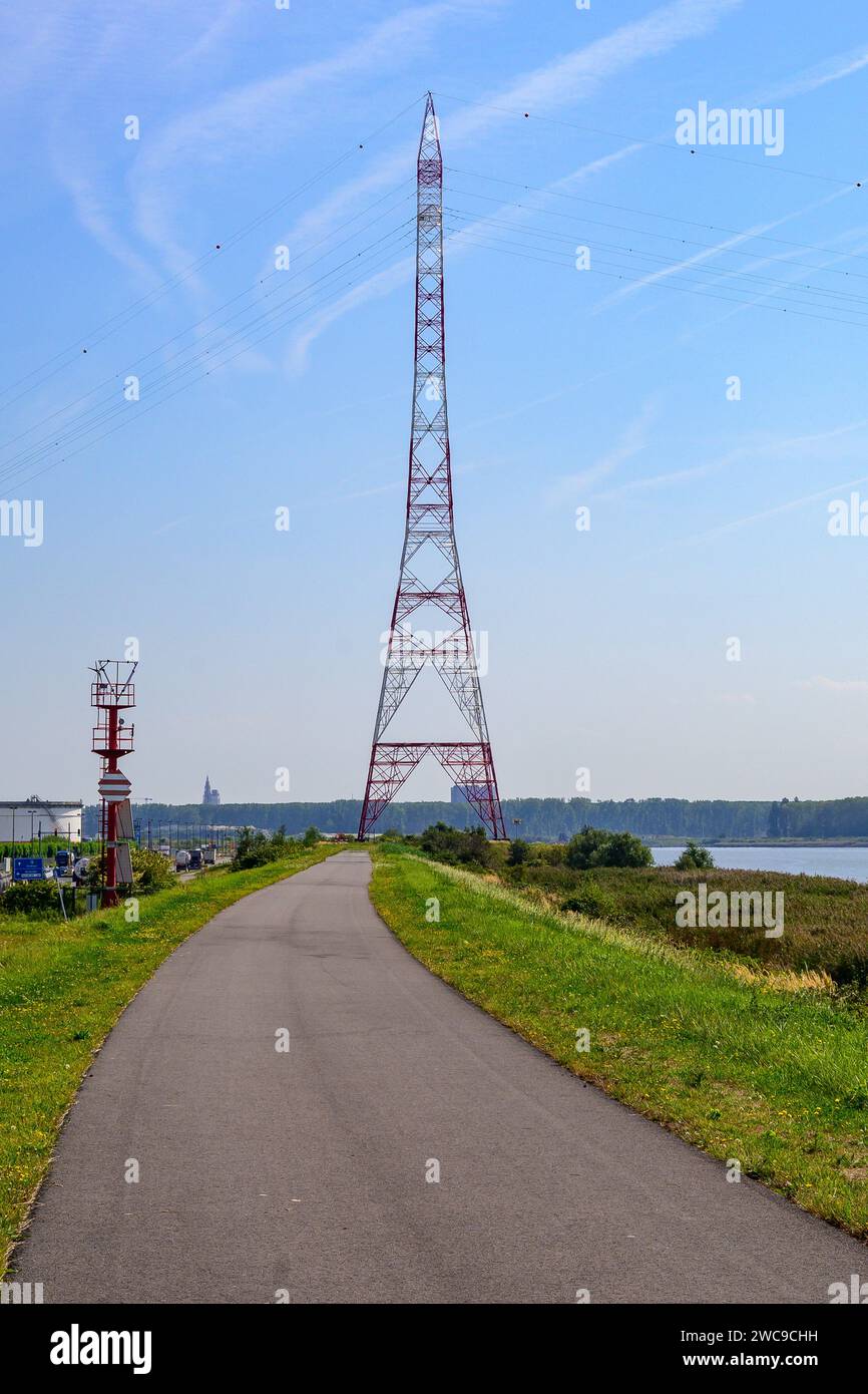 An asphalted road to a red electricity pylon next to the water in Port ...