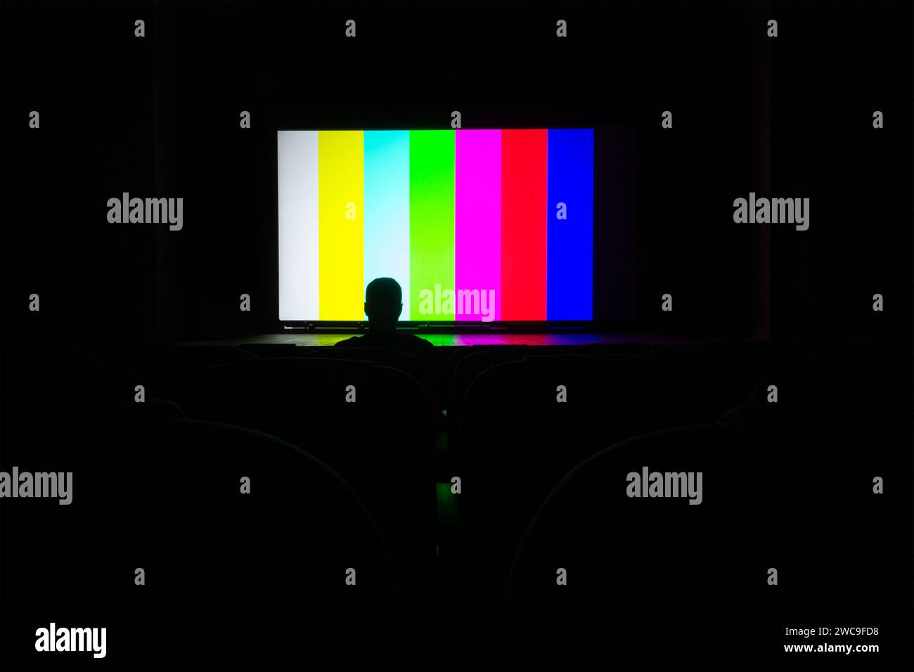 Silhouette of a man, a lone spectator sitting in a chair in the cinema ...
