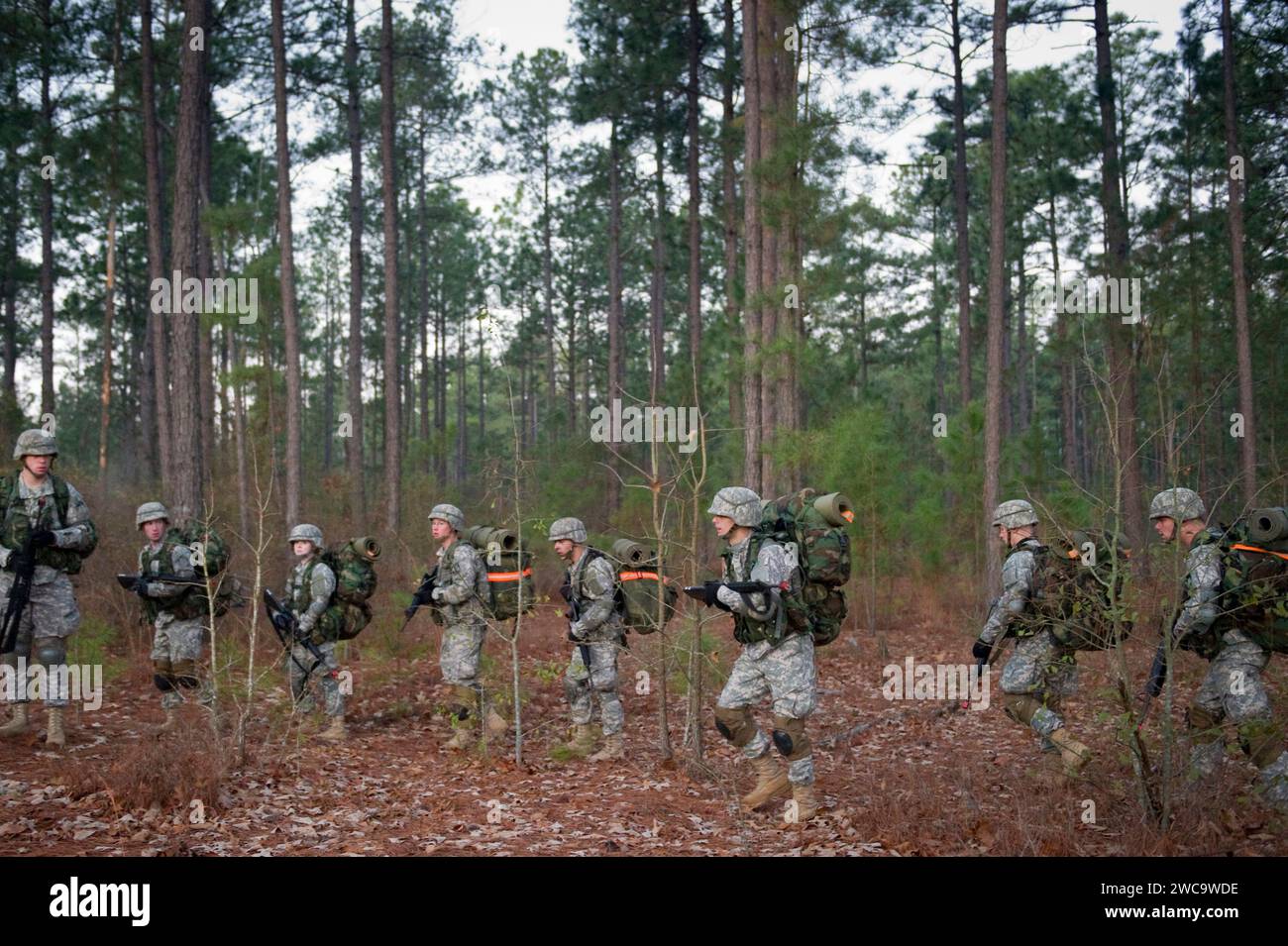 Soldiers march in a column formation with their rucks and weapons ...