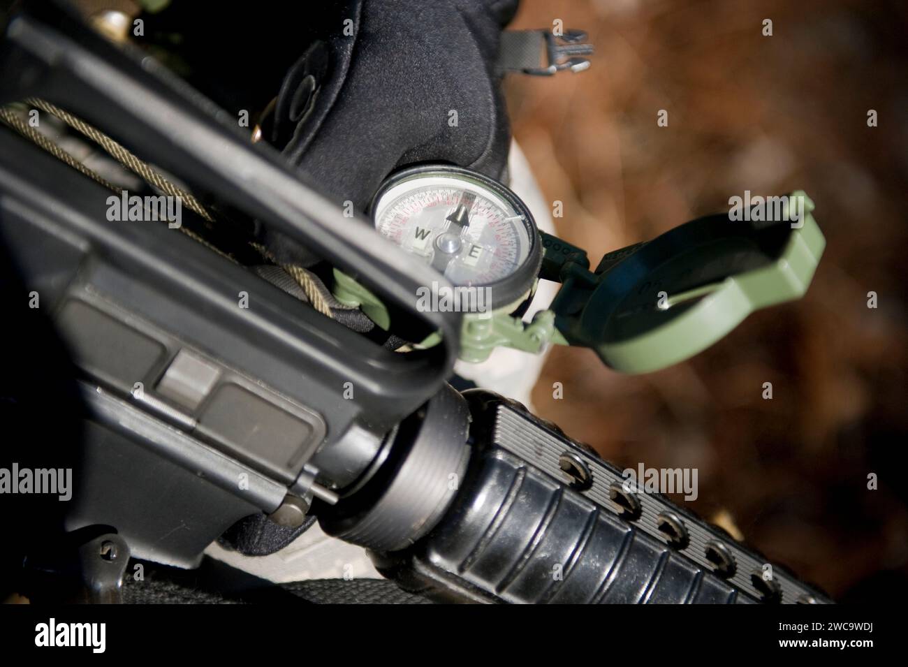 A soldier uses a compass to navigate through the woods during a field ...