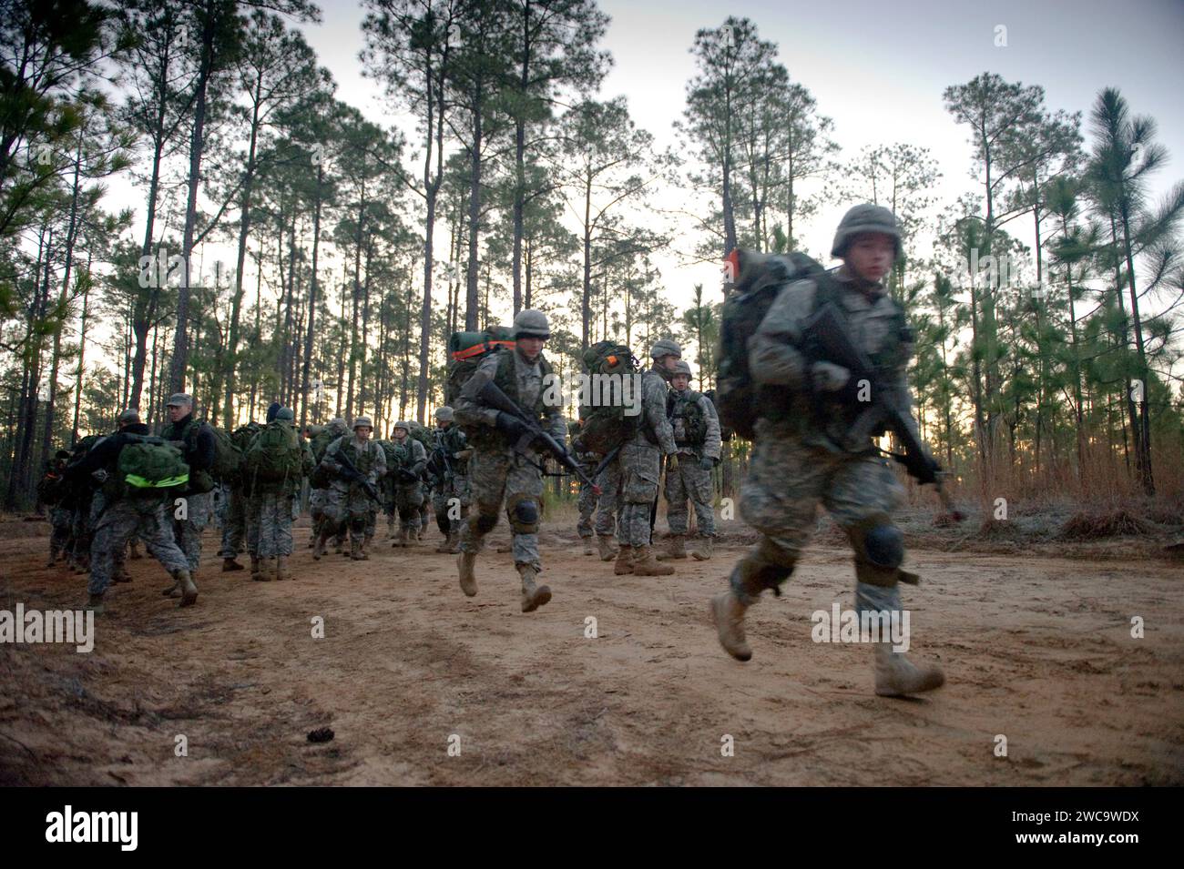 Soldiers run down a dirt road with their rucks and weapons during a ...