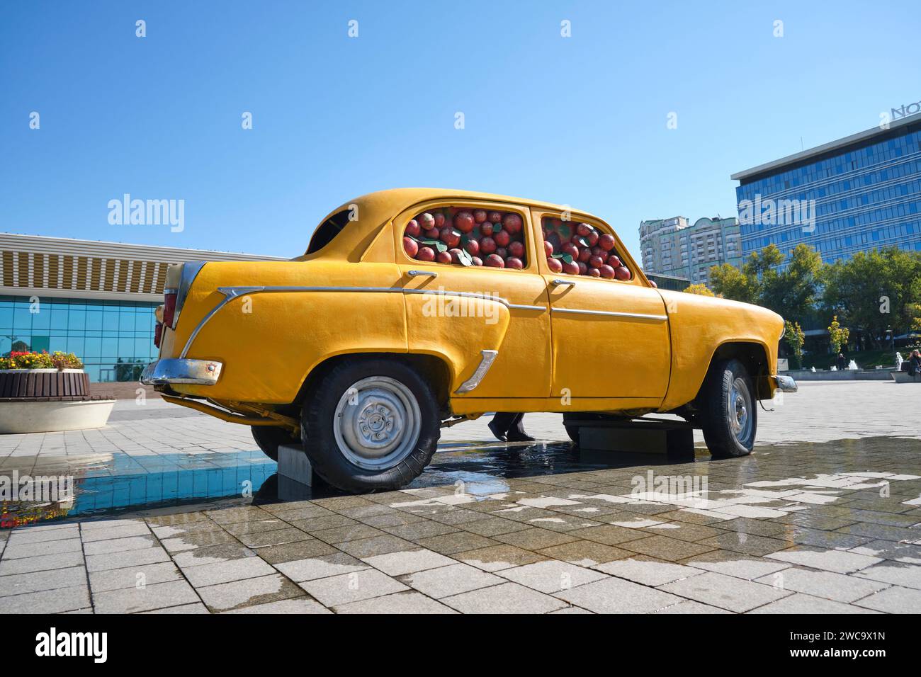 An old yellow Moskvich car, filled with fake red apples. It is an art ...