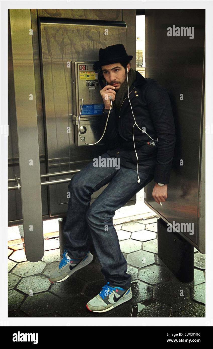 Young man in phone booth smoking Stock Photo - Alamy